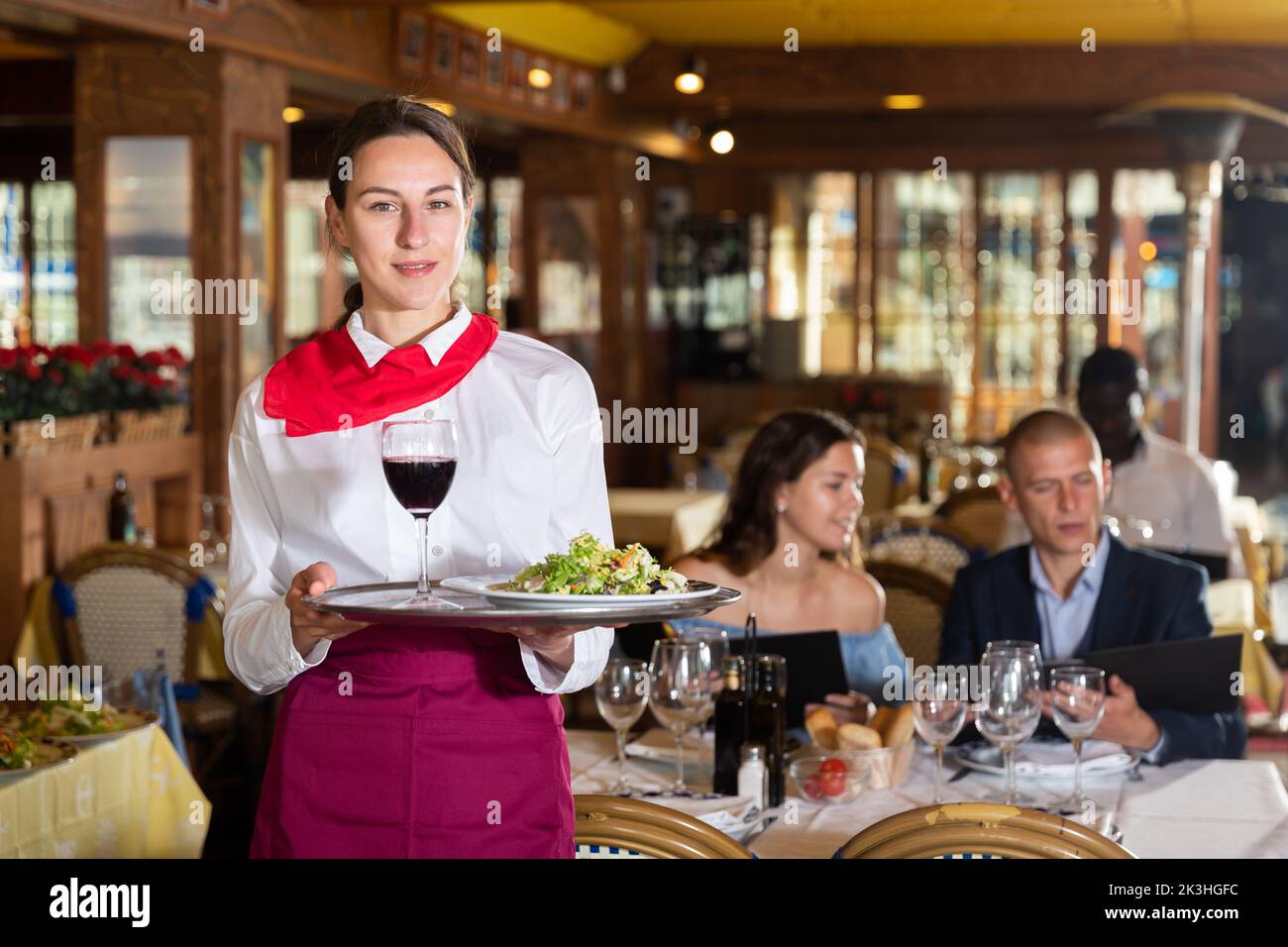Waiter holding tray at restaurant with customers behind him Stock Photo ...