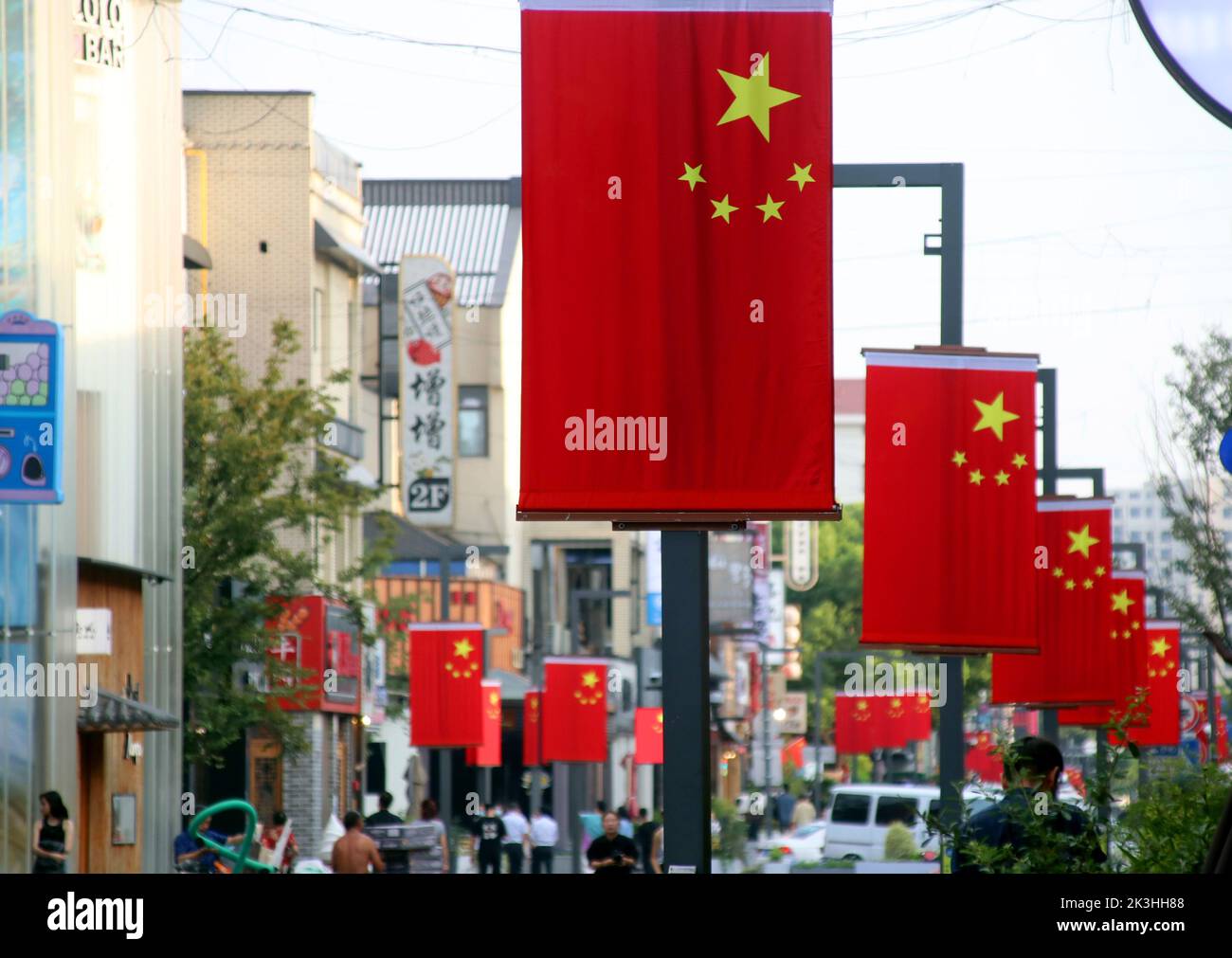 SUZHOU, CHINA - SEPTEMBER 26, 2022 - People pass under national flags ...