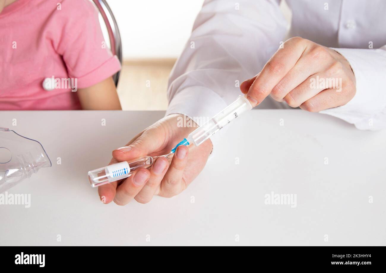 A doctor is putting a drug into a nebulizer for the treatment of ...
