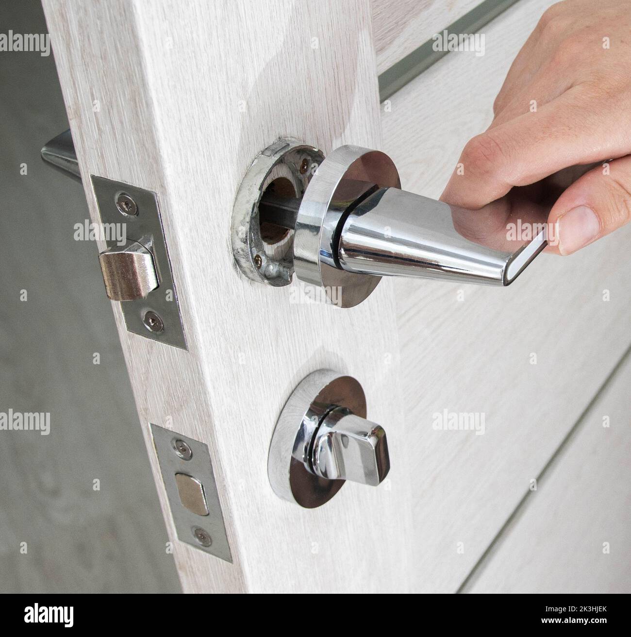 A man's hand opens an interior door with a broken doorknob. Poor ...