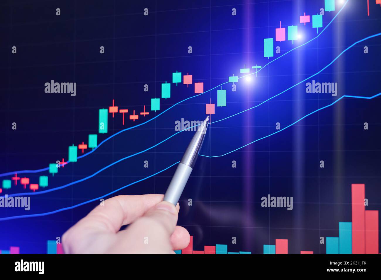 The trader points with a pen at the Rising stock chart on the monitor ...
