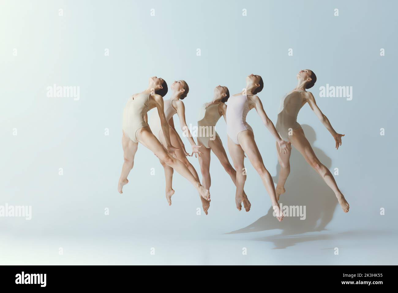 Group of young girls, ballet dancers performing, posing isolated over grey studio background ...