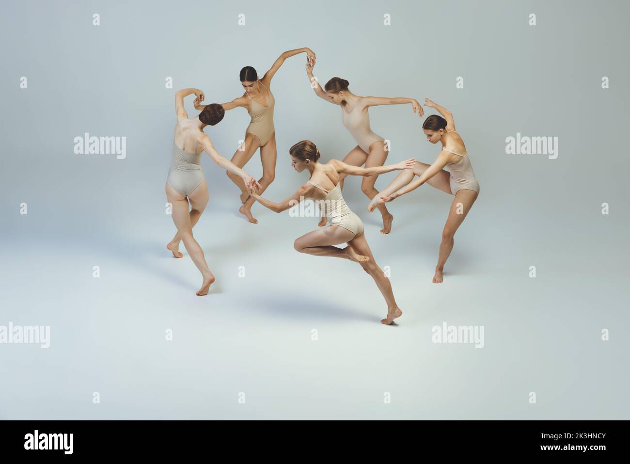 Group of young girls, ballet dancers performing, posing isolated over grey studio background ...