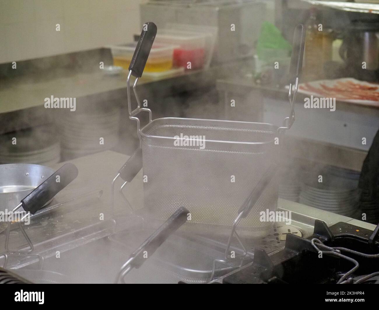 chef in white uniform pouring boiled spaghetti into pan wok for cooking ...