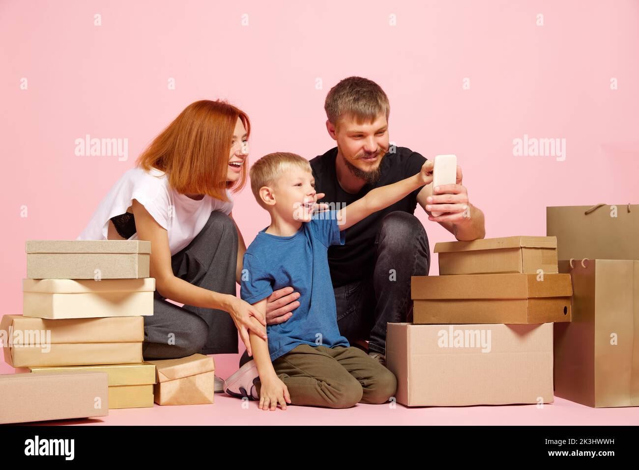 Happy mother, father and son open cardboard boxes, receive parcels ...