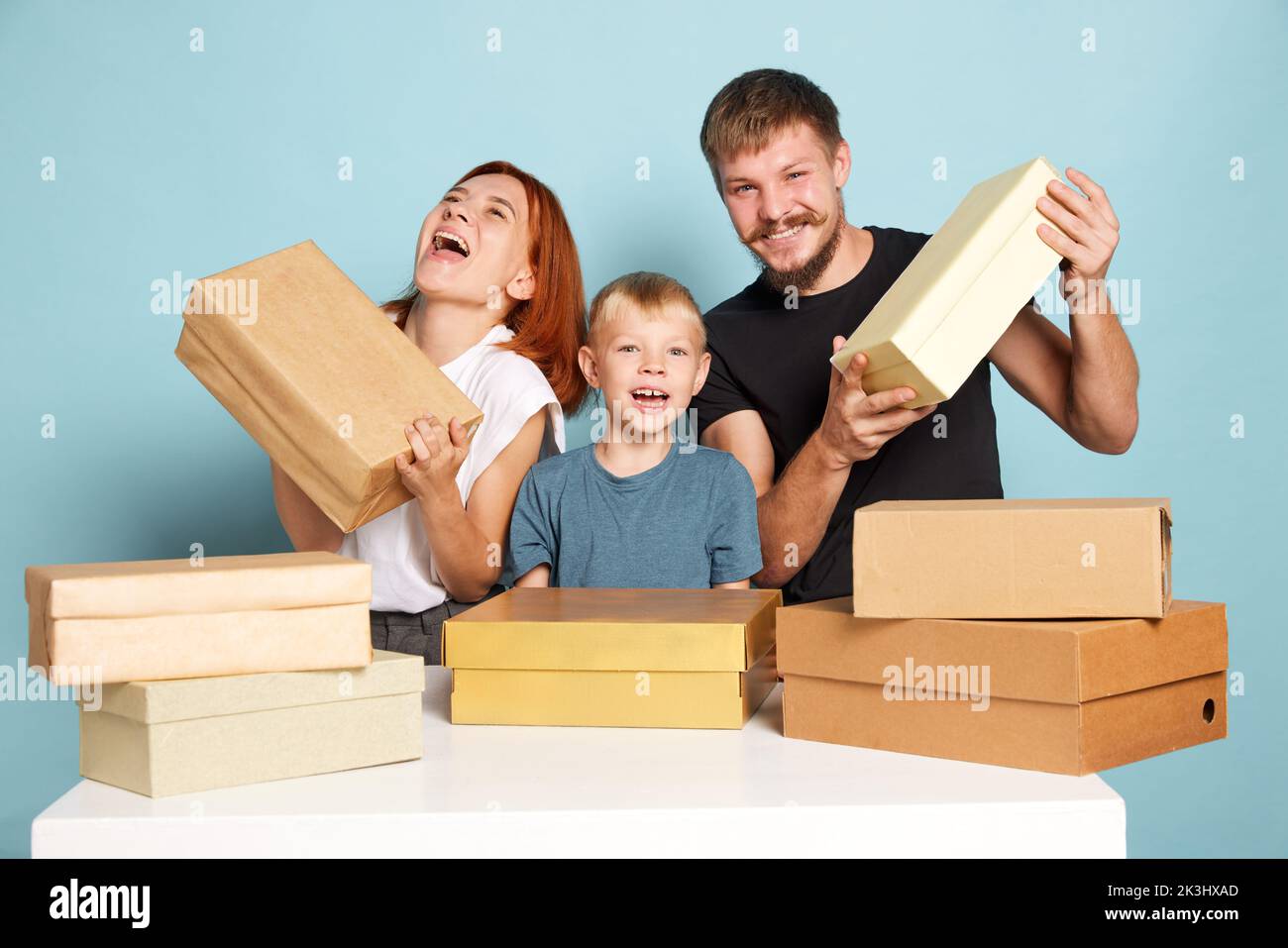 Unpacking. Friendly family, parents and child open cardboard boxes ...