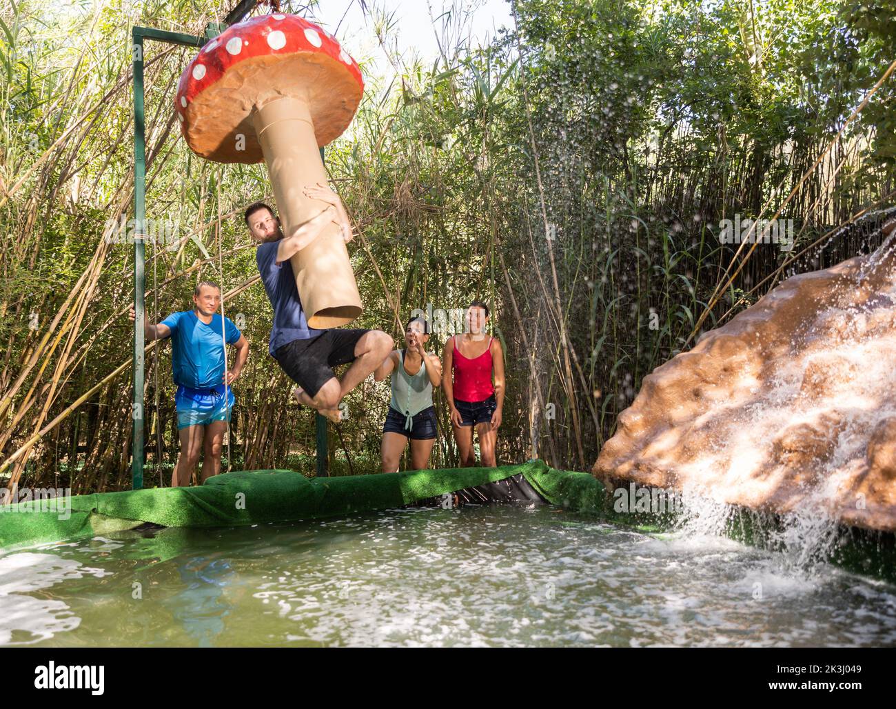 Cheerful guy flying over pool of water on fly agaric in amusement park ...