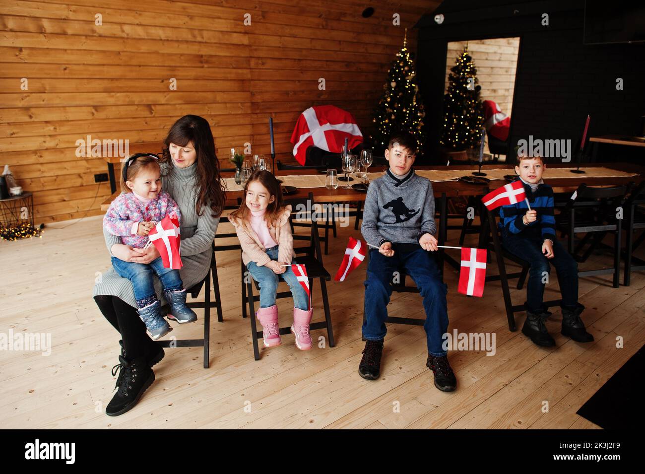 Family with Denmark flags inside wooden house sitting by table. Travel ...