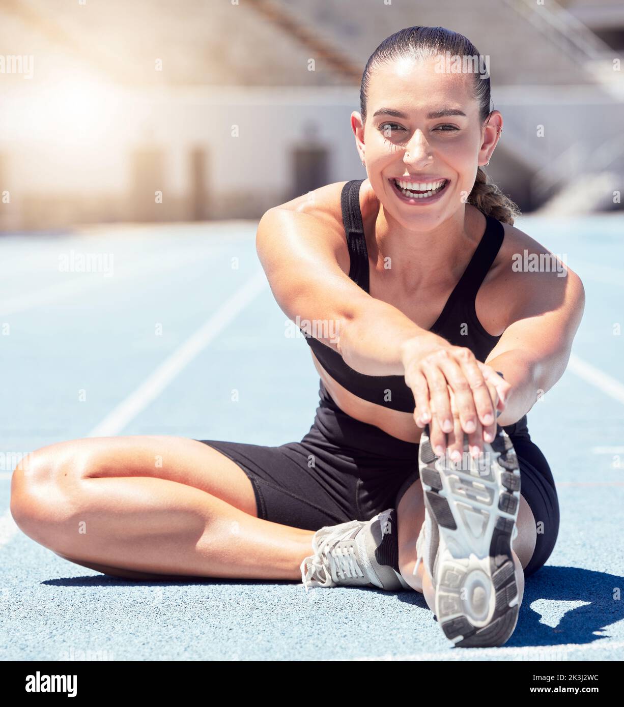 Happy fitness or sports woman stretching at stadium in sunshine lens flare for healthy lifestyle ...