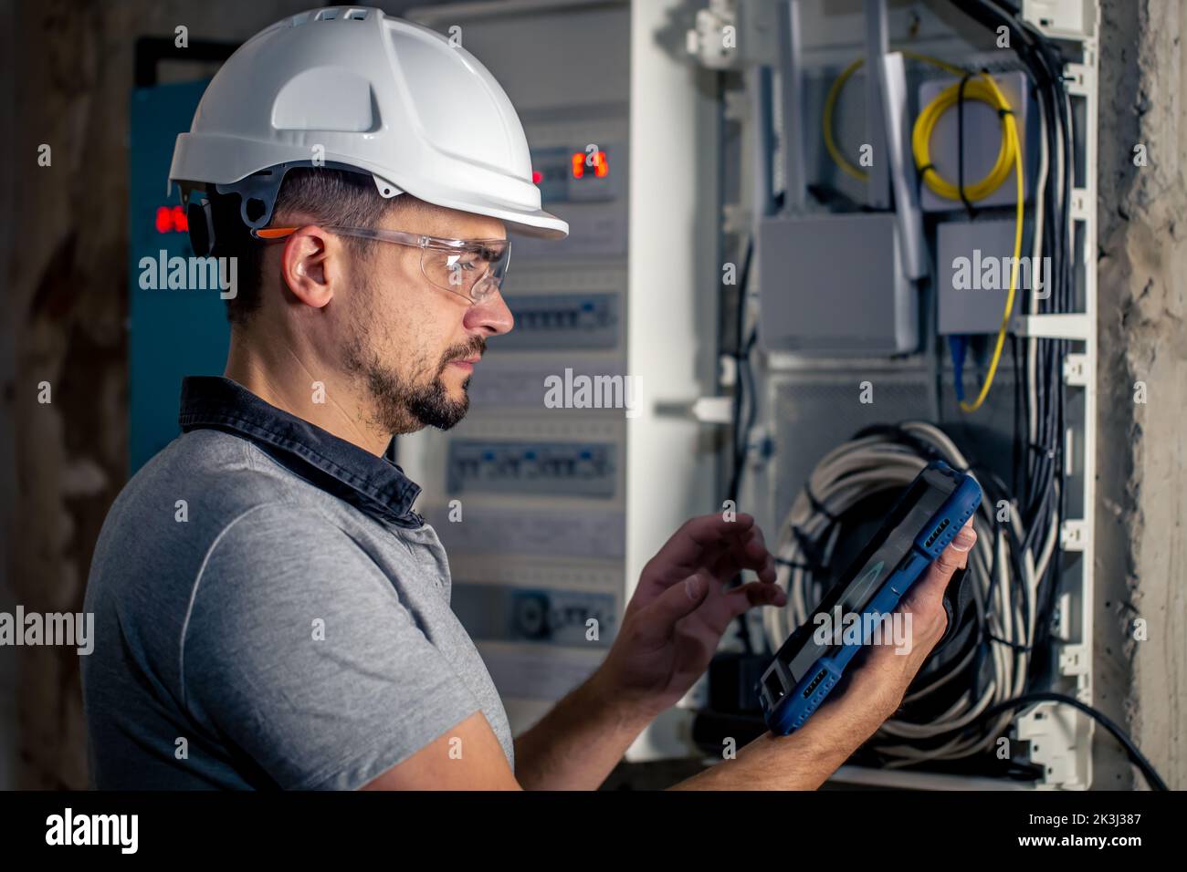 Man, an electrical technician working in a switchboard with fuses, uses ...