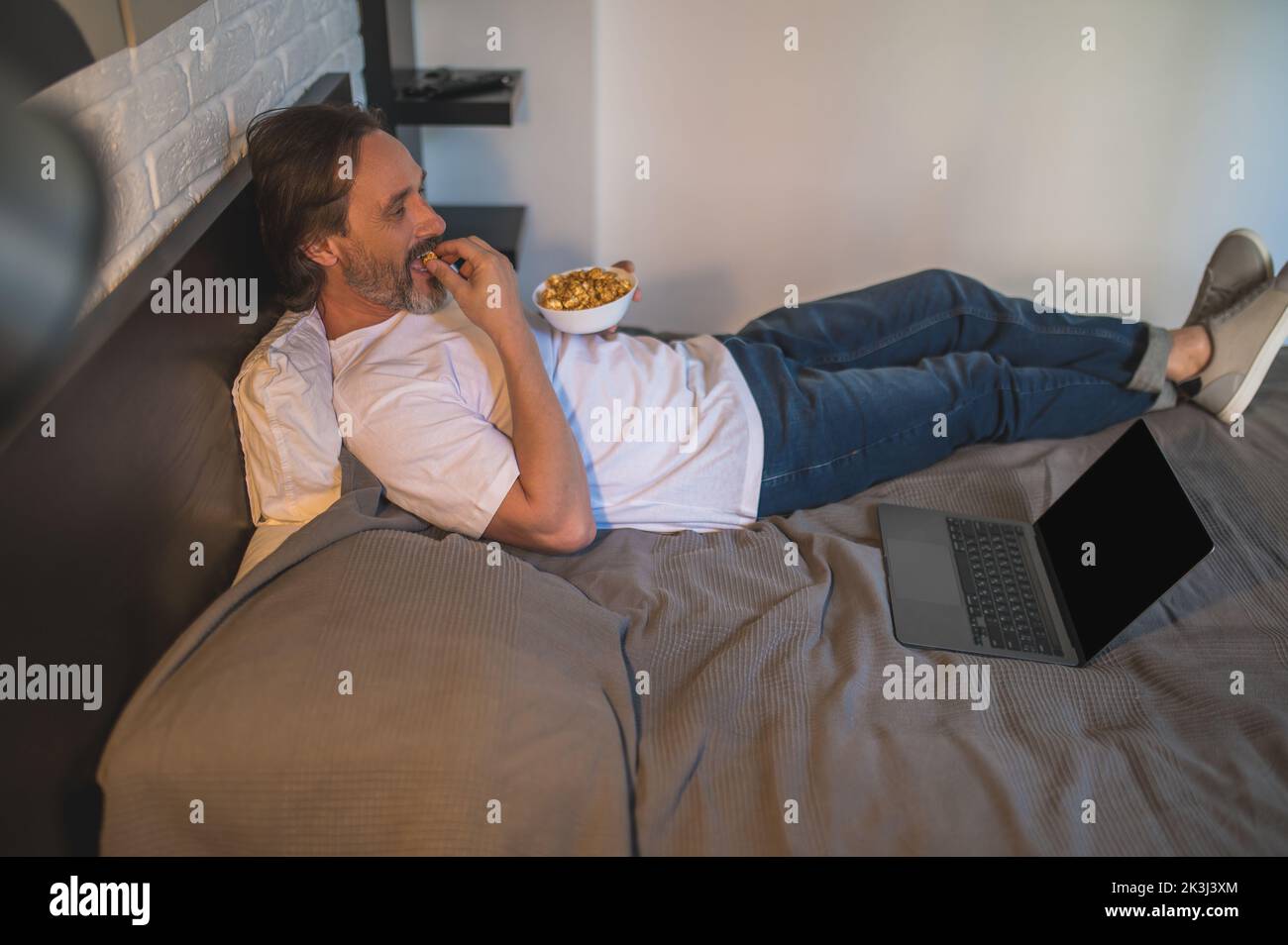 Man lying on the bed and watching something on internet Stock Photo - Alamy