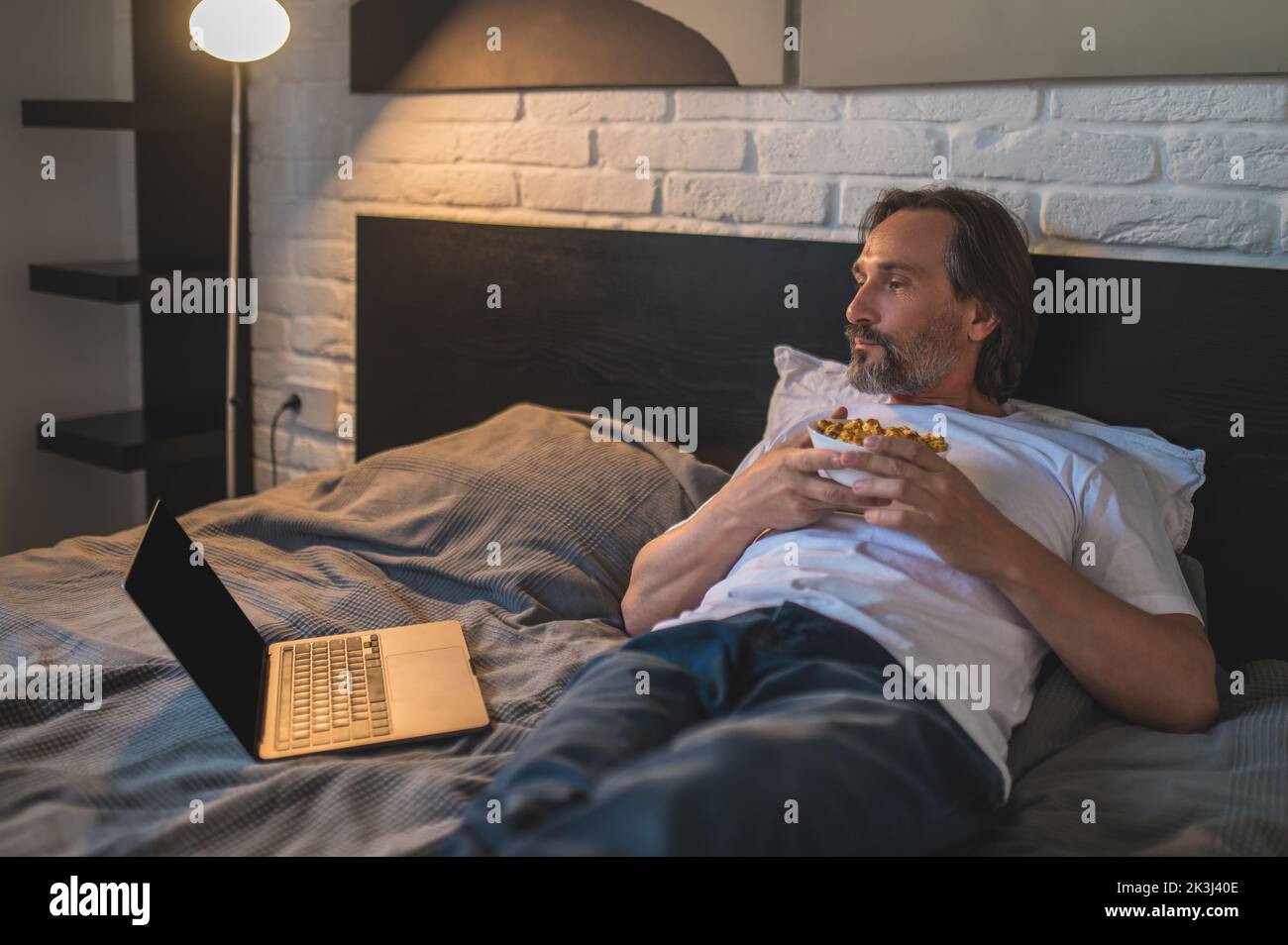 Man lying on the bed and watching something on internet Stock Photo - Alamy