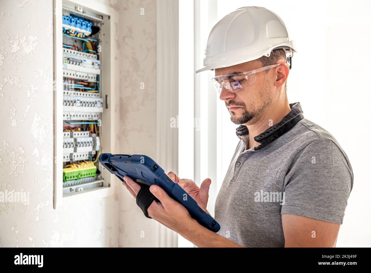 Man, an electrical technician working in a switchboard with fuses, uses a tablet Stock Photo - Alamy