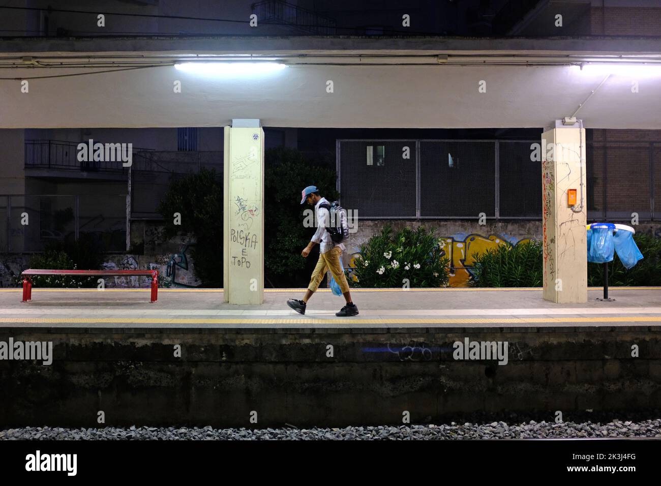 A man walking alone at night on an Italian train platform near ...