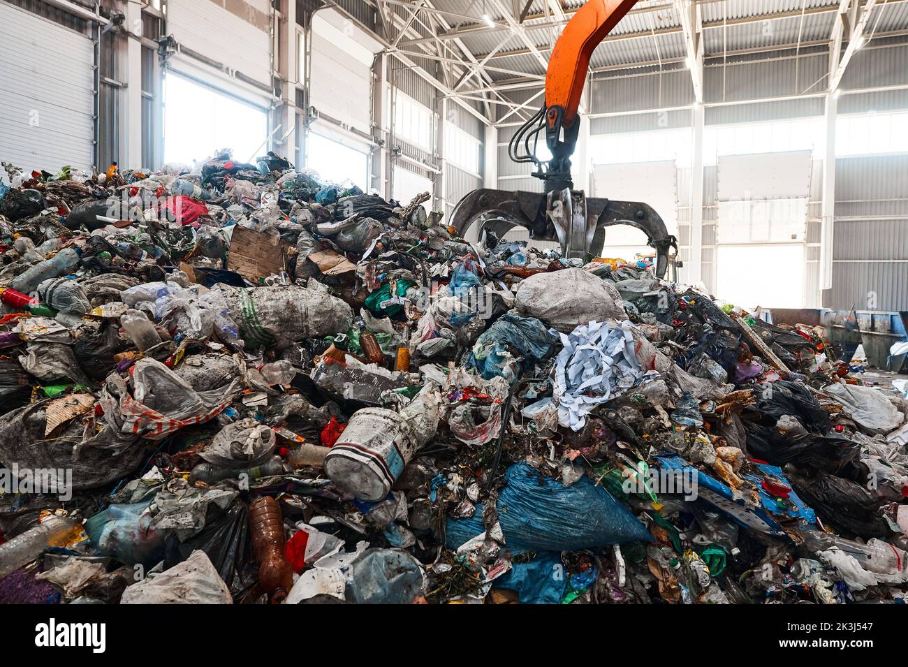 Excavator grabs trash in warehouse of waste processing plant Stock ...