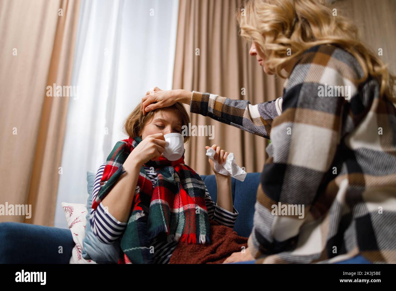Mature mother takes care of her daughter who is sick with the flu ...