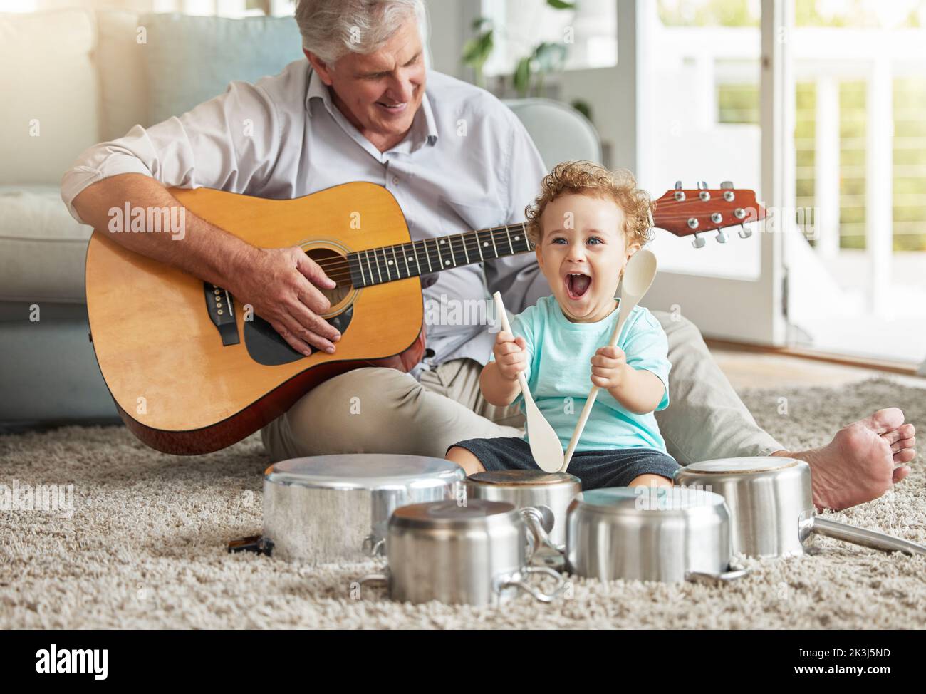 Music, pots and baby drummer with old man on living room floor with pan ...