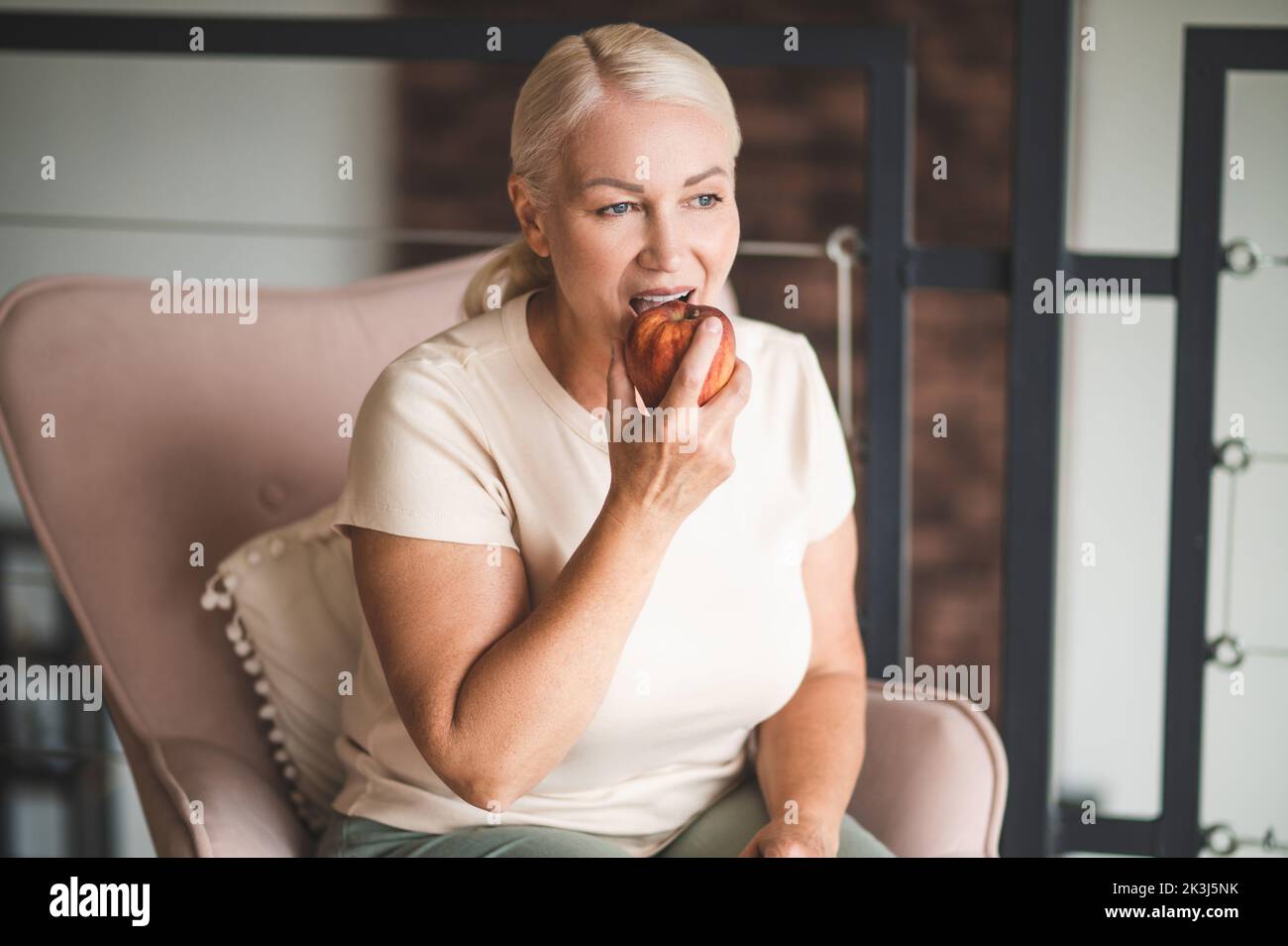 Hungry lady biting off a piece of fruit Stock Photo - Alamy