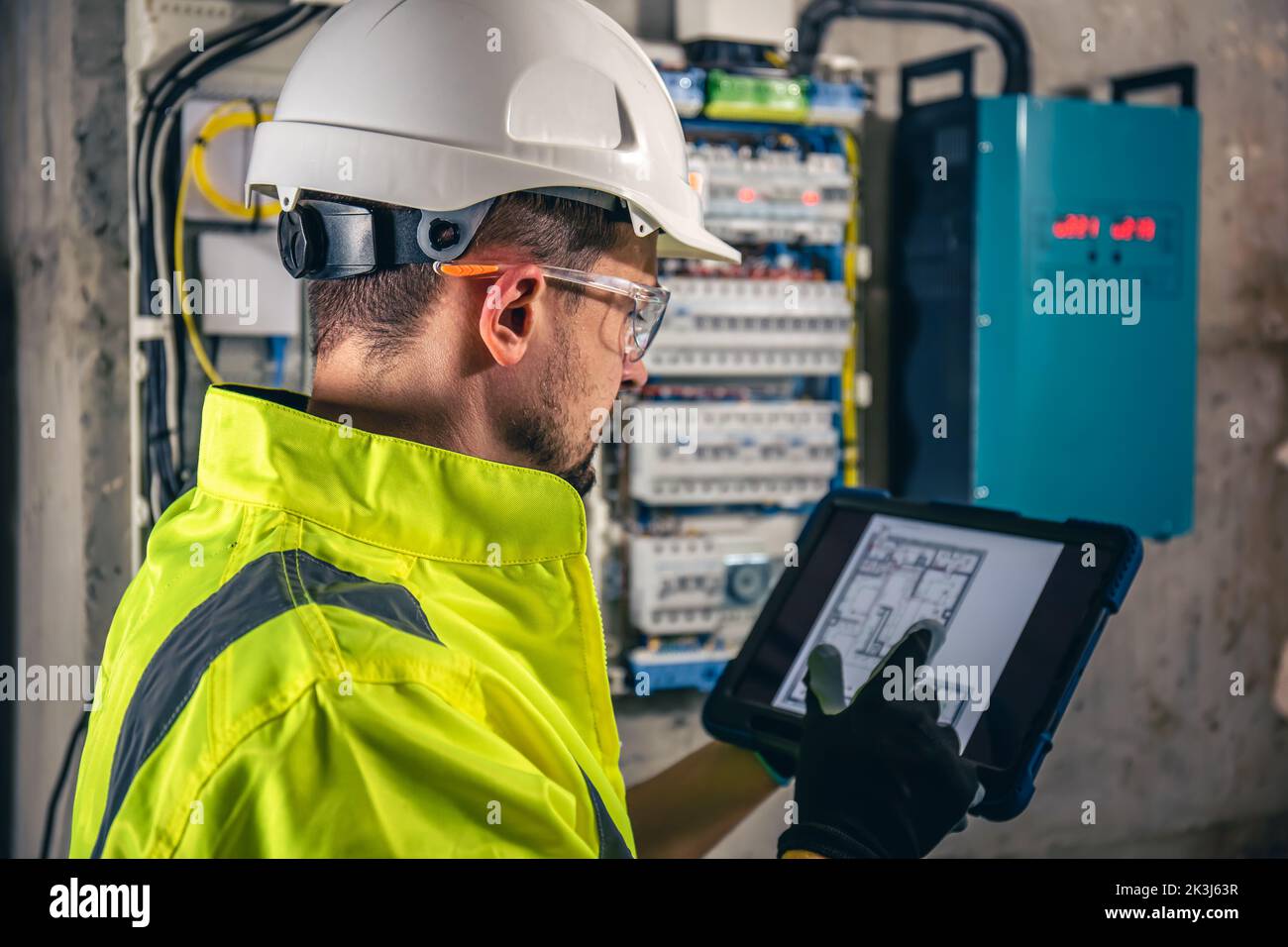 Man, an electrical technician working in a switchboard with fuses, uses a tablet Stock Photo - Alamy