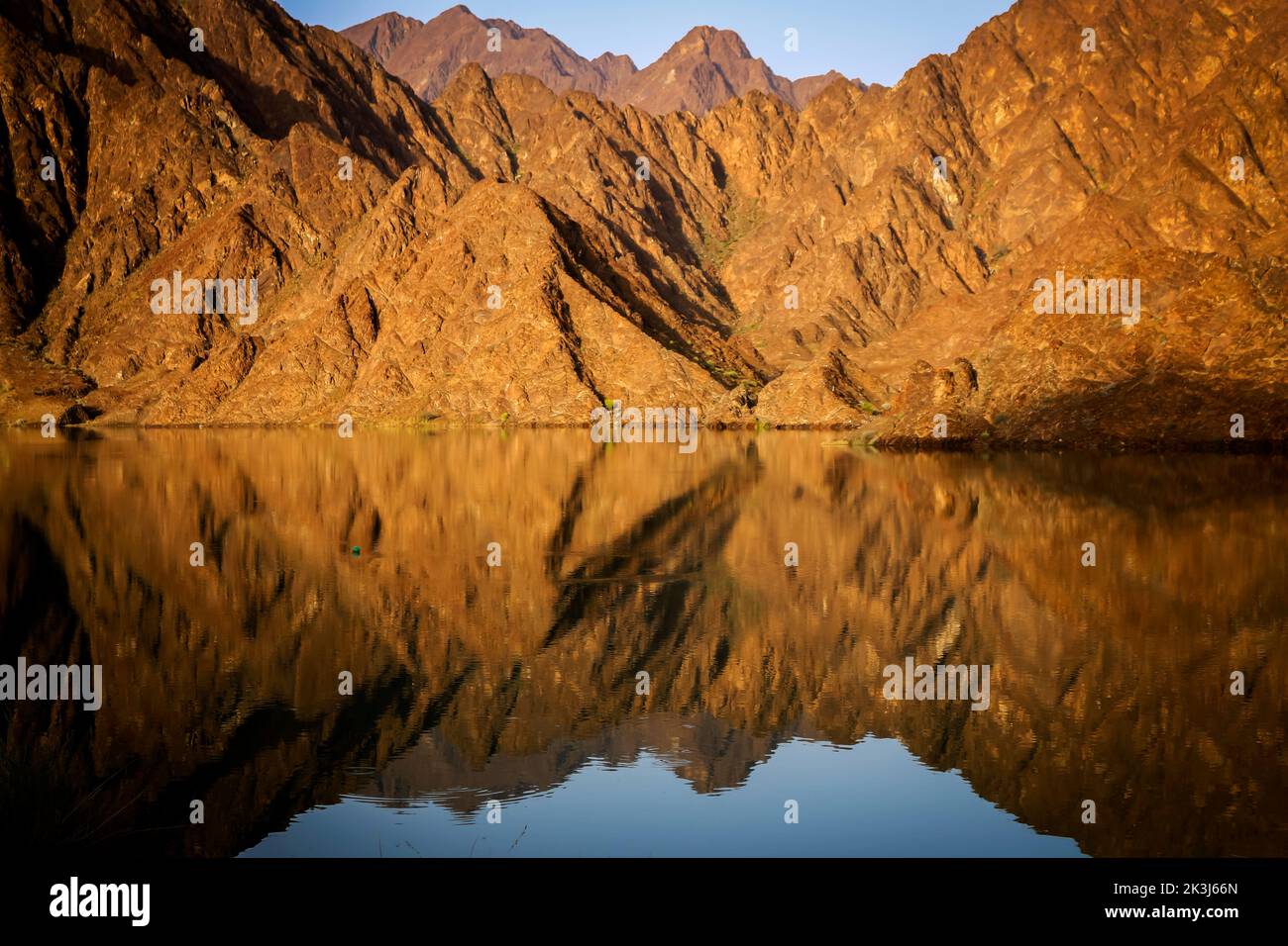 Beautiful deep green Hatta lake with rocky Hajar Mountains on ...