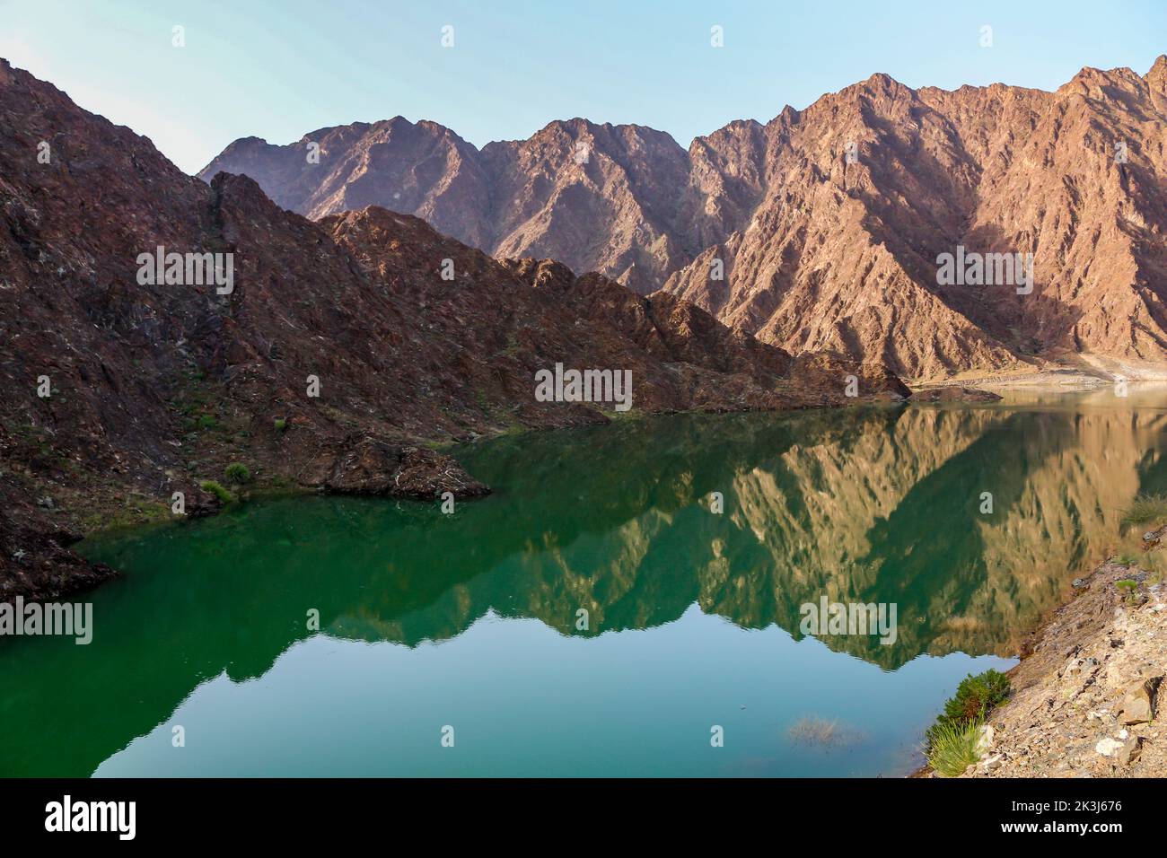 Beautiful deep green Hatta lake with rocky Hajar Mountains on ...
