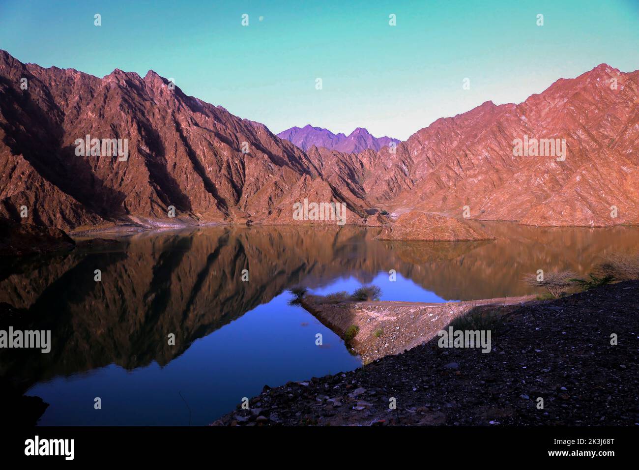 Beautiful deep green Hatta lake with rocky Hajar Mountains on ...