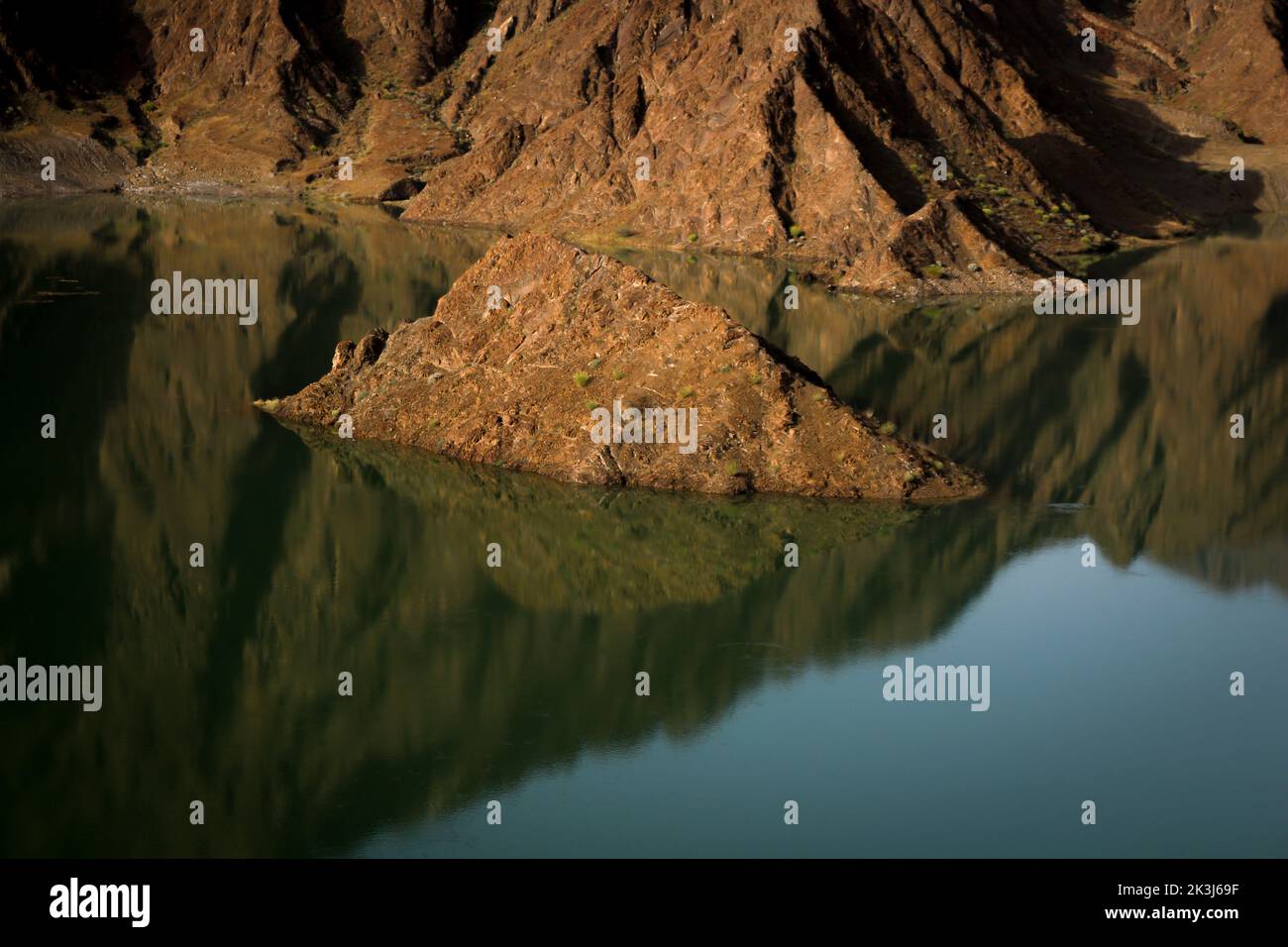 Beautiful deep green Hatta lake with rocky Hajar Mountains on ...