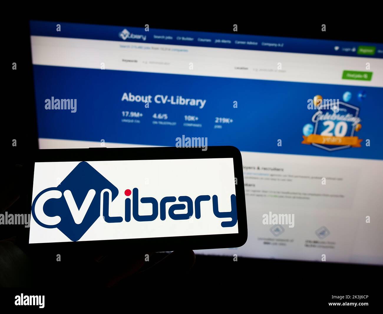 Person holding mobile phone with logo of British job board company CV-Library Ltd. on screen in ...