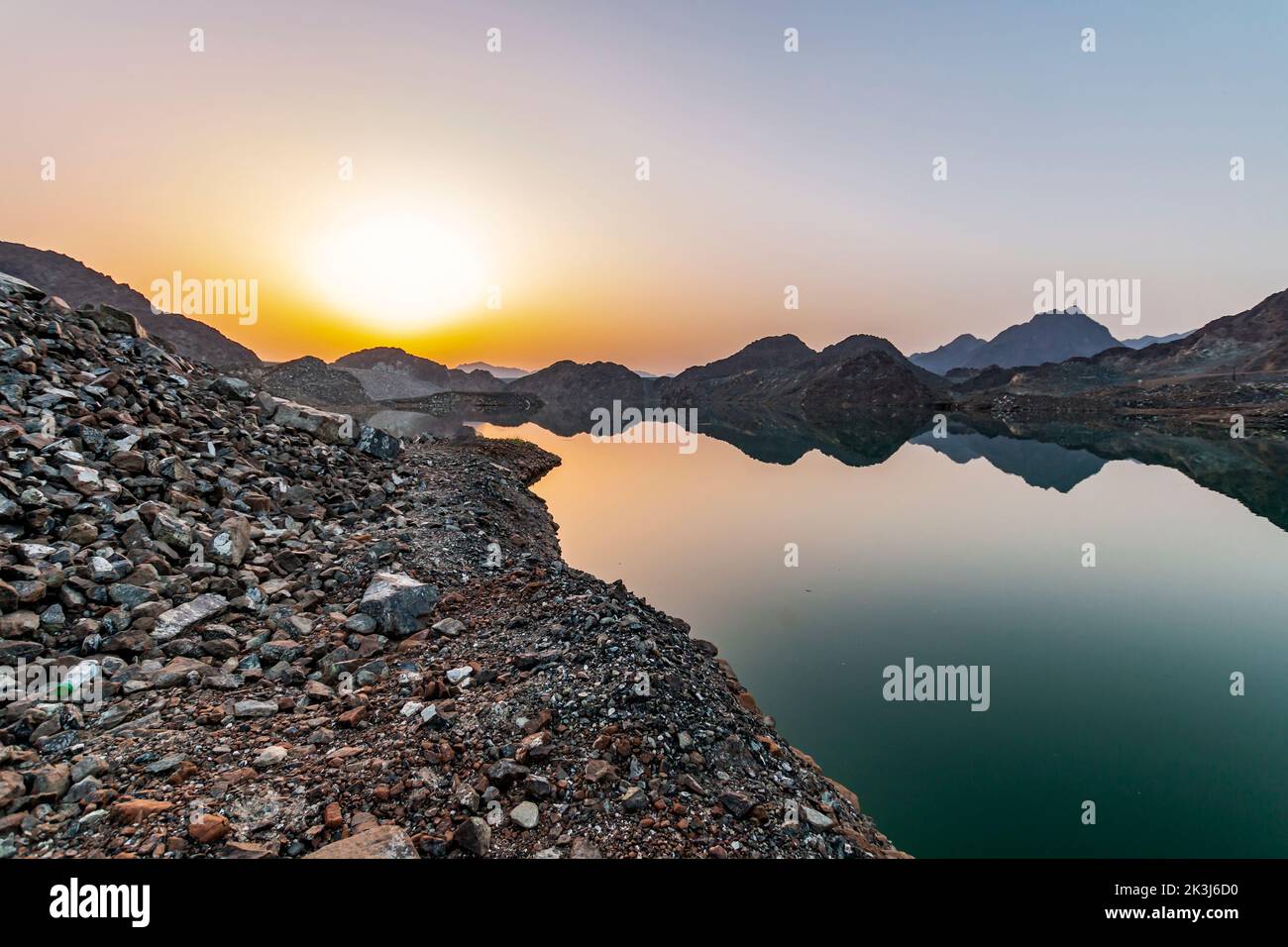 Beautiful deep green Hatta lake with rocky Hajar Mountains on background. Overview of Hatta dam ...