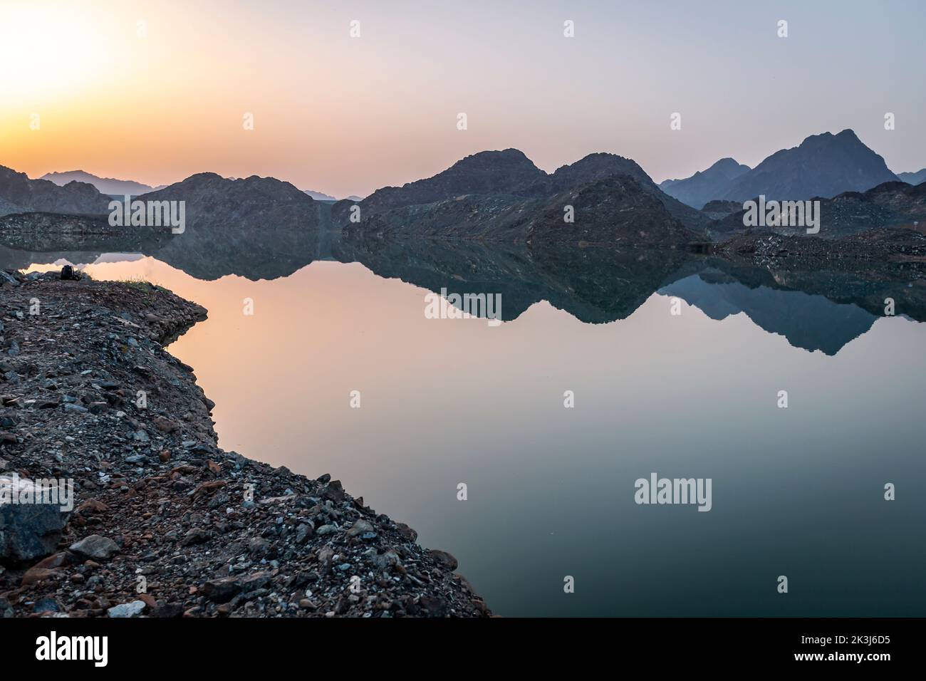 Beautiful deep green Hatta lake with rocky Hajar Mountains on ...