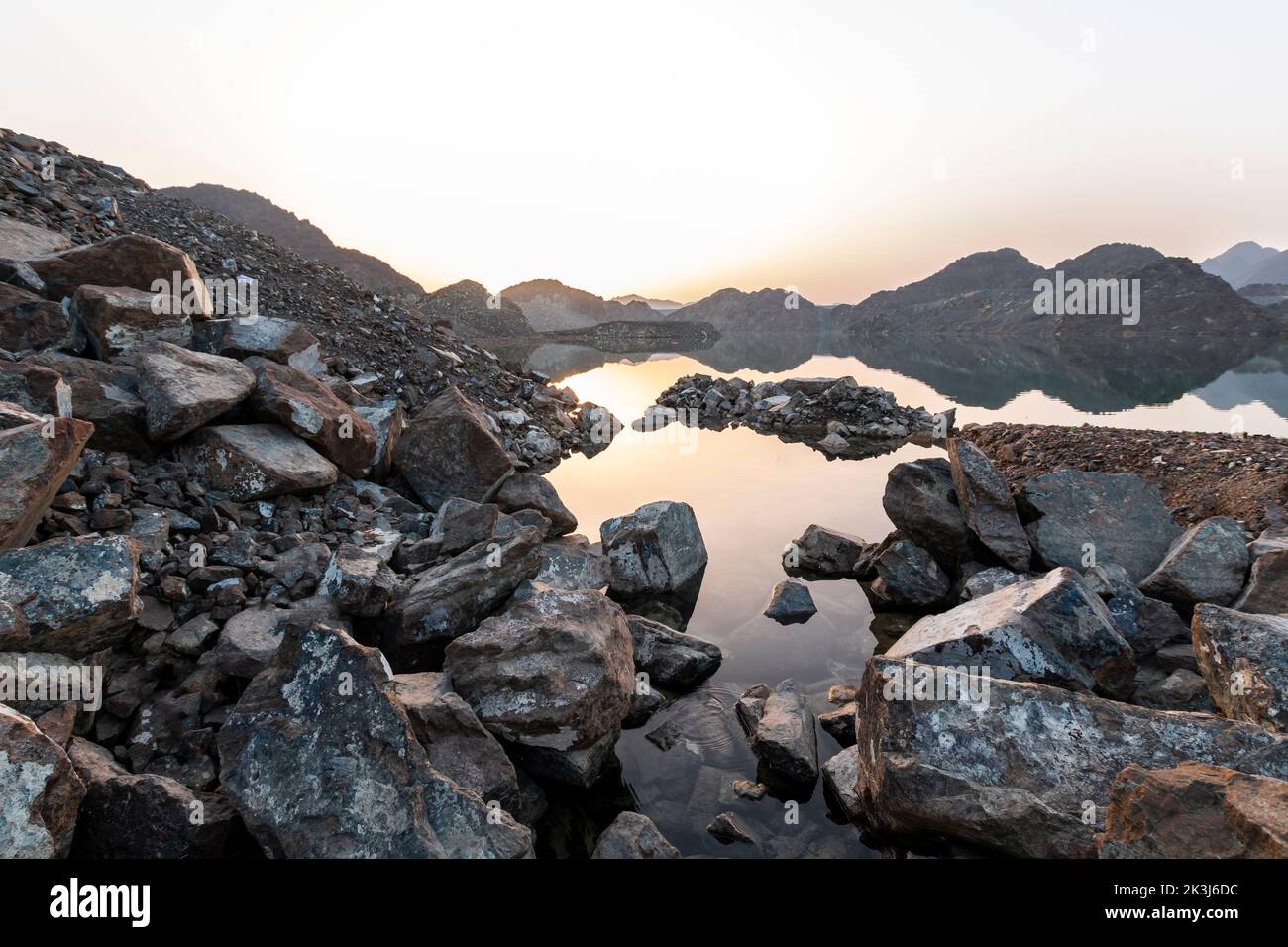 Beautiful deep green Hatta lake with rocky Hajar Mountains on ...