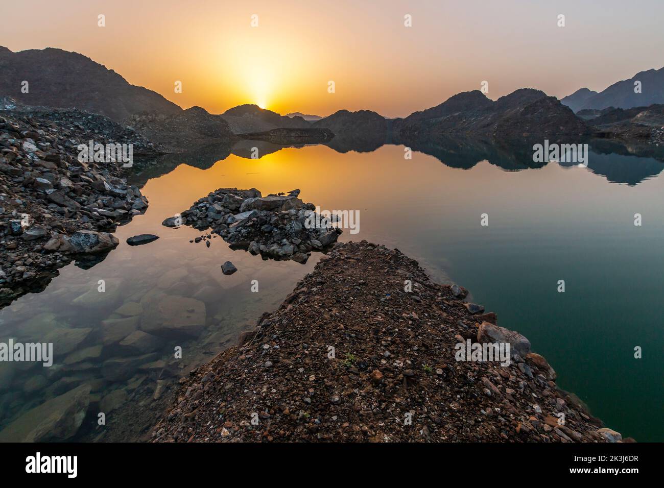 Beautiful deep green Hatta lake with rocky Hajar Mountains on ...