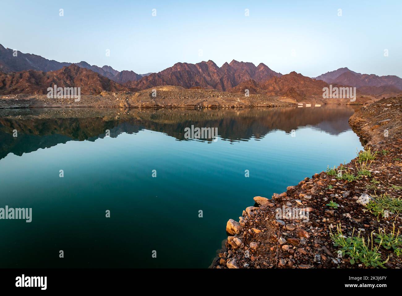 Beautiful deep green Hatta lake with rocky Hajar Mountains on ...