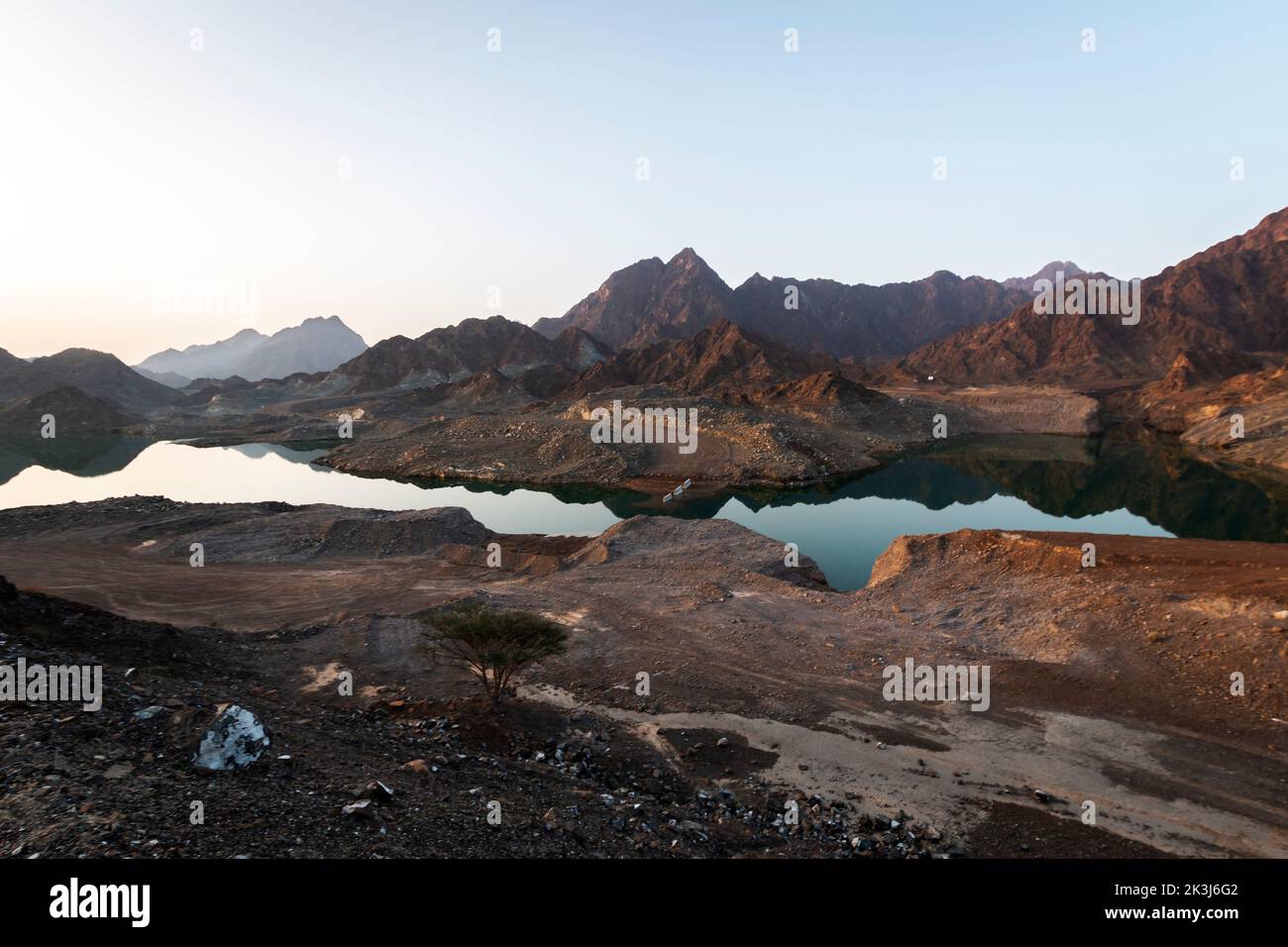 Beautiful deep green Hatta lake with rocky Hajar Mountains on background. Overview of Hatta dam ...