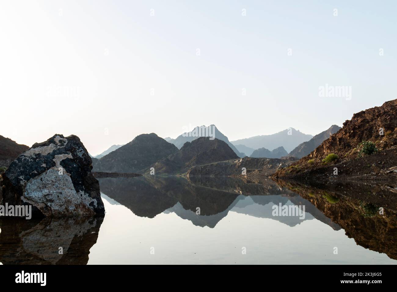 Beautiful deep green Hatta lake with rocky Hajar Mountains on ...
