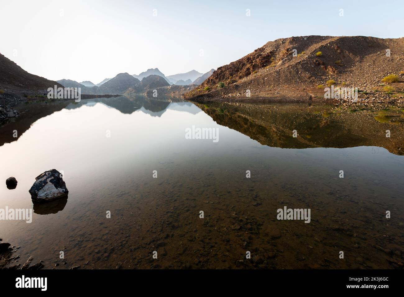 Beautiful deep green Hatta lake with rocky Hajar Mountains on ...