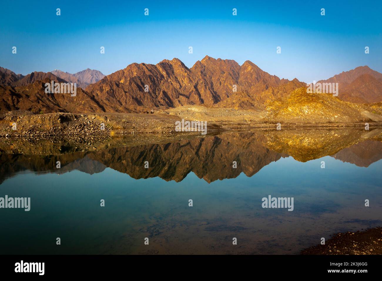 Beautiful deep green Hatta lake with rocky Hajar Mountains on ...