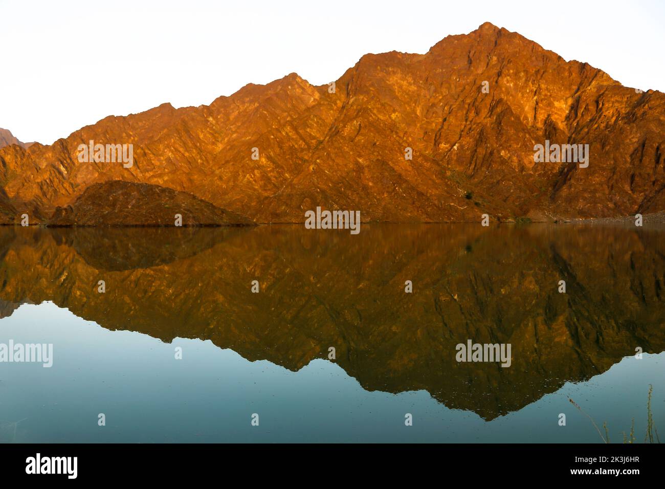 Beautiful deep green Hatta lake with rocky Hajar Mountains on ...