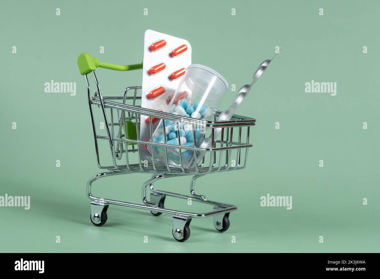 several different packages of pills in small shopping car on green ...