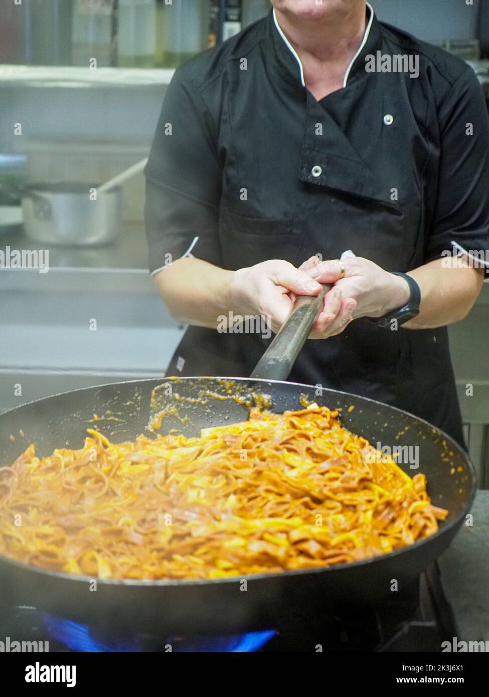 mixing pasta with sauce in a big professional used professional pan ...