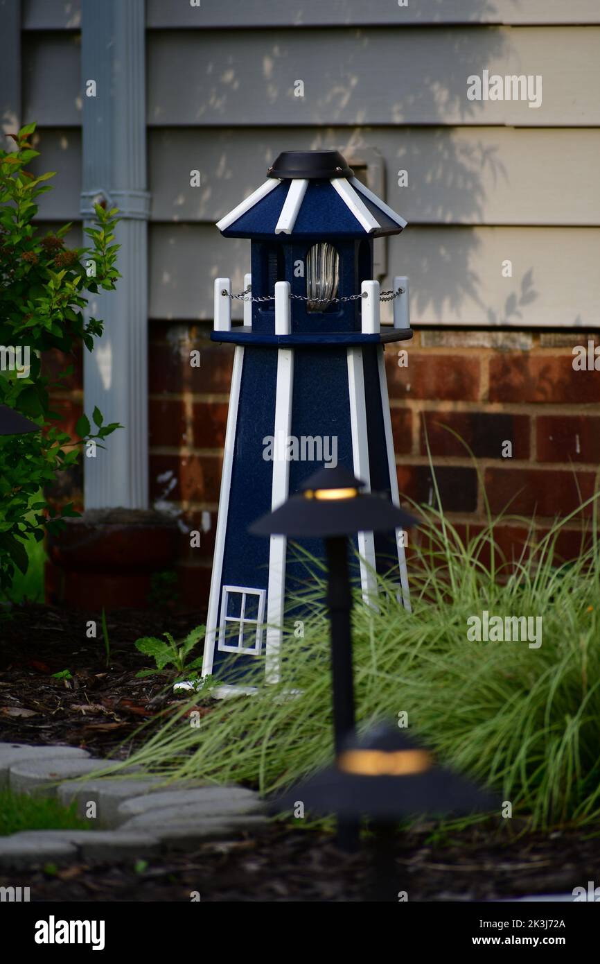 A vertical shot of a miniature blue lighthouse in a flower bed of a ...