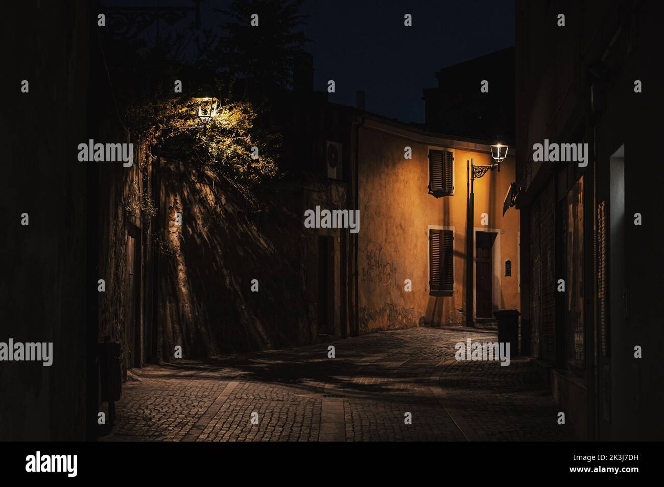 A stone floor of an old street between dark ancient buildings with ...