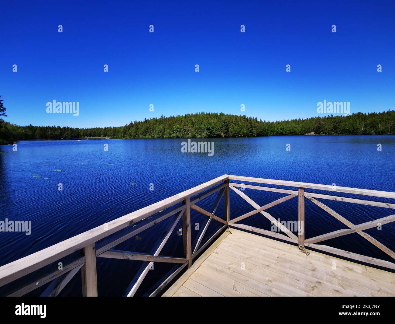 A blue lake view from a wooden boardwalk with a shallow covered with ...
