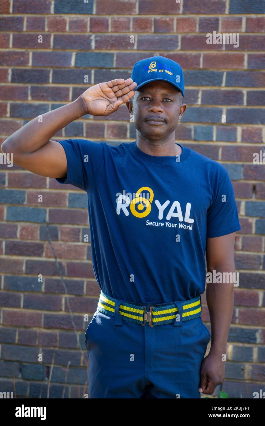 A vertical shot of a male security guard saluting at attention with the ...