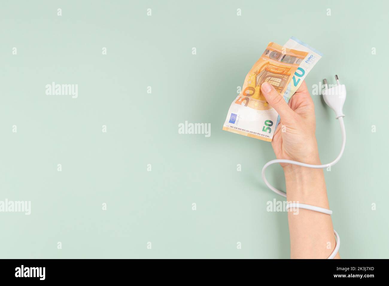 Electric power cord wraps around woman hand holding Euroo banknotes ...