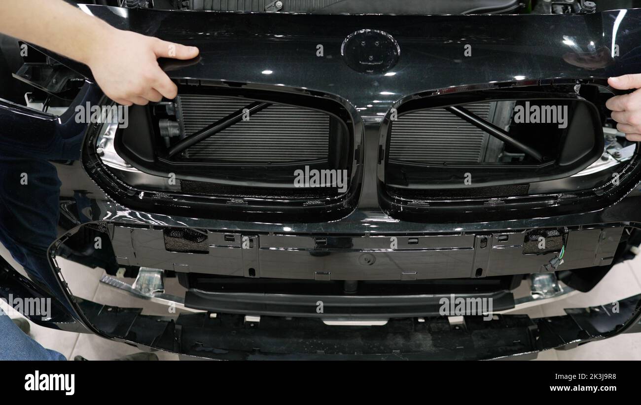 Installation of the front bumper on the car. Car repair in the workshop ...