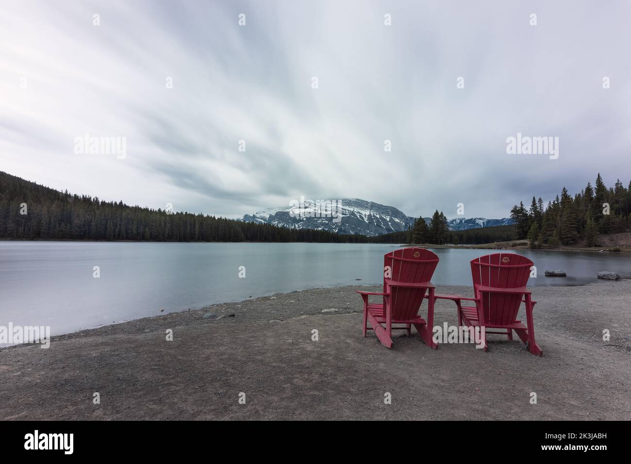 A beautiful view of two red chairs on the beach looking at the water ...