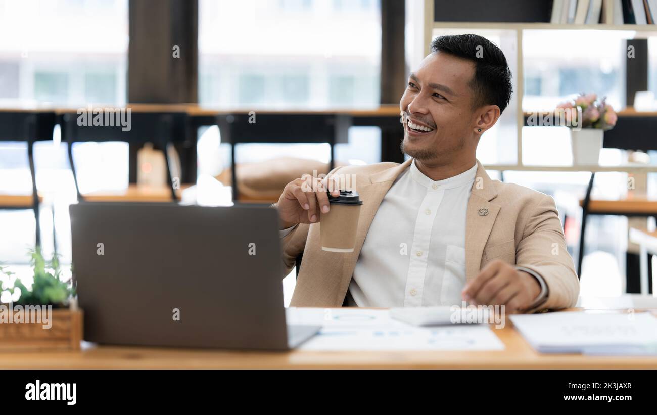 Asian Businessman smiling and working to analyze technical price graph ...