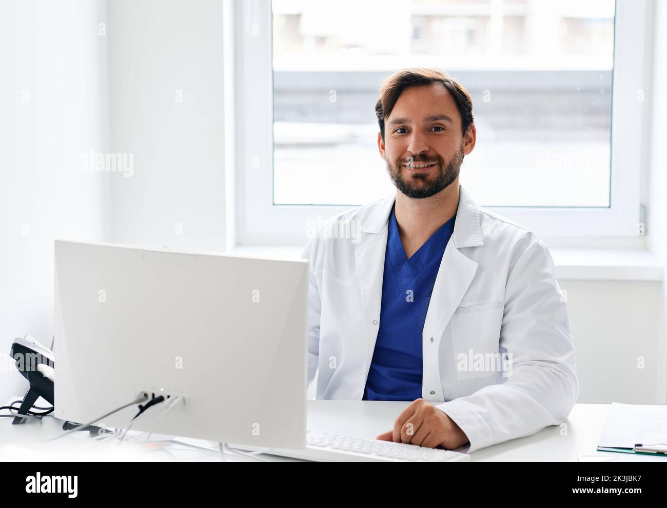Portrait of smiling general practitioner wearing doctor's uniform ...