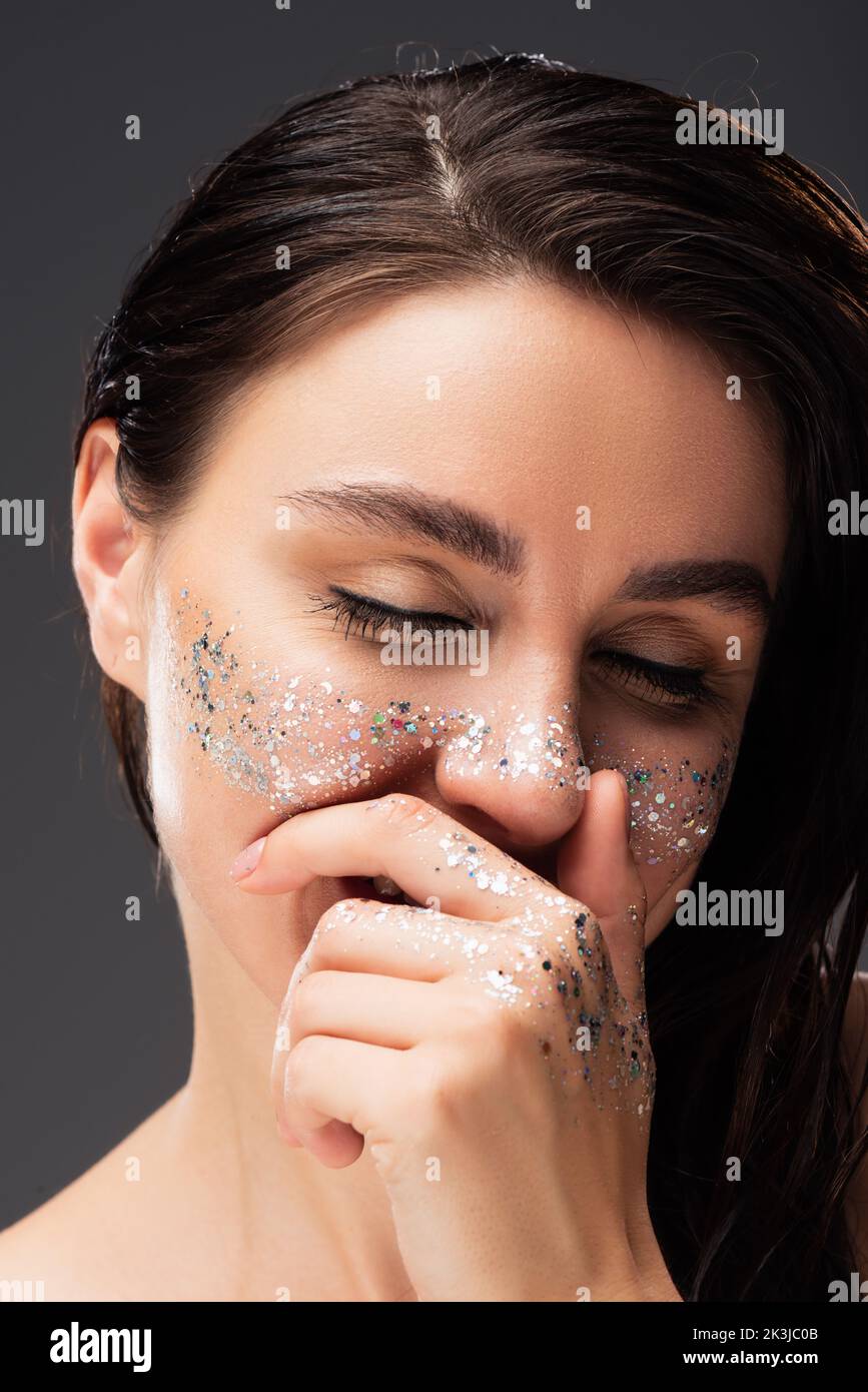 portrait of young brunette woman with sparkling glitter on cheeks ...